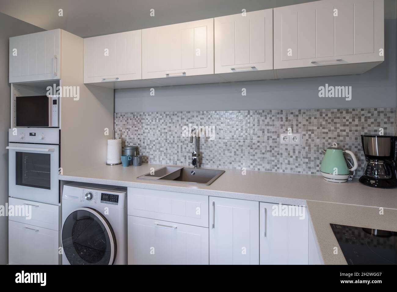 Modern interior of stylish white kitchen with appliances. Washing ...