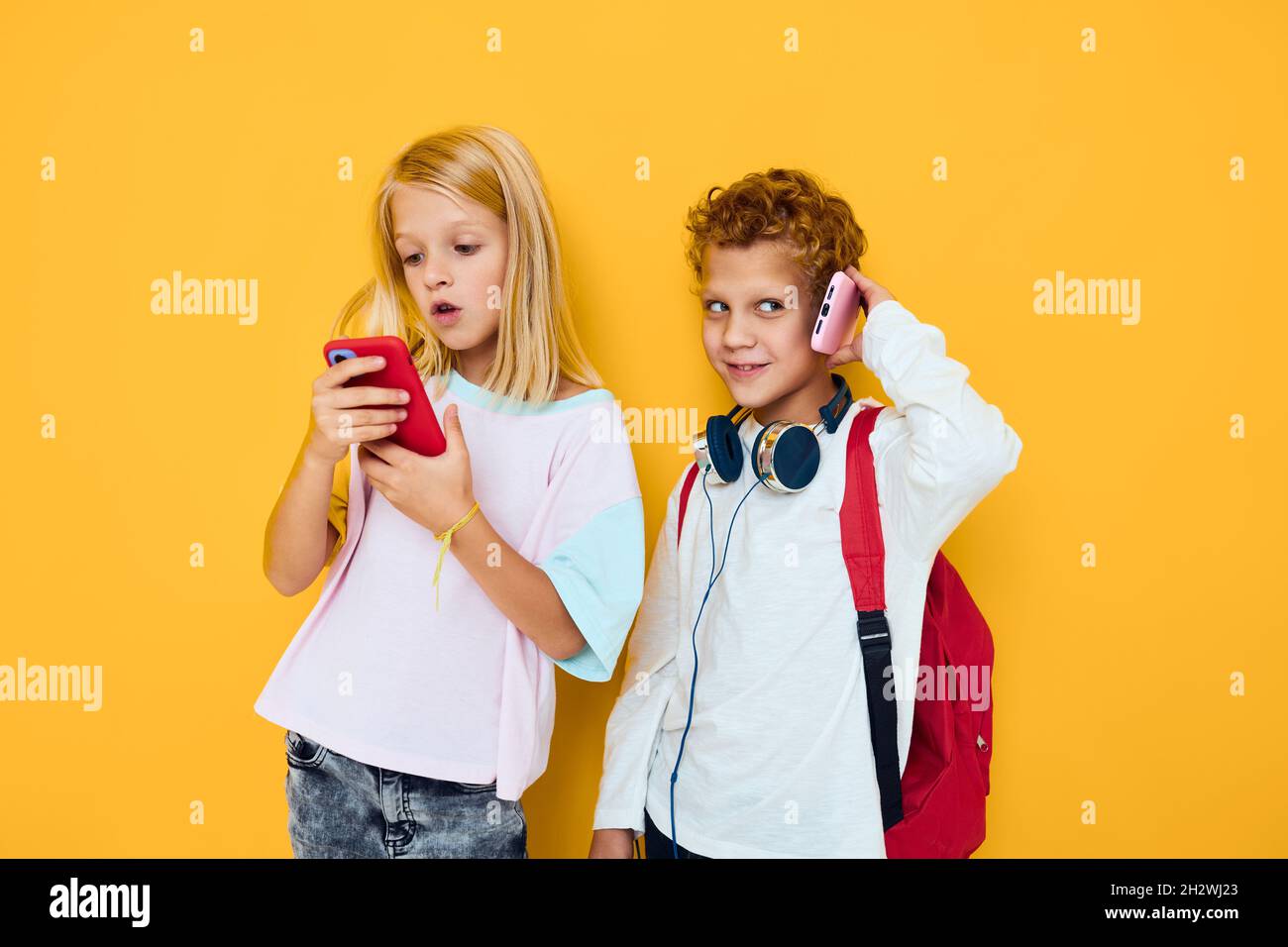 teenage boy and girl use gadgets with headphones yellow background ...
