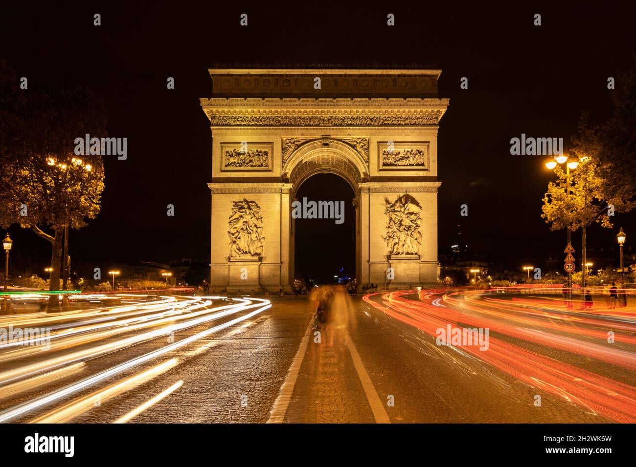 The famous Arc de Triomphe monument in Paris with traffic lights trails ...