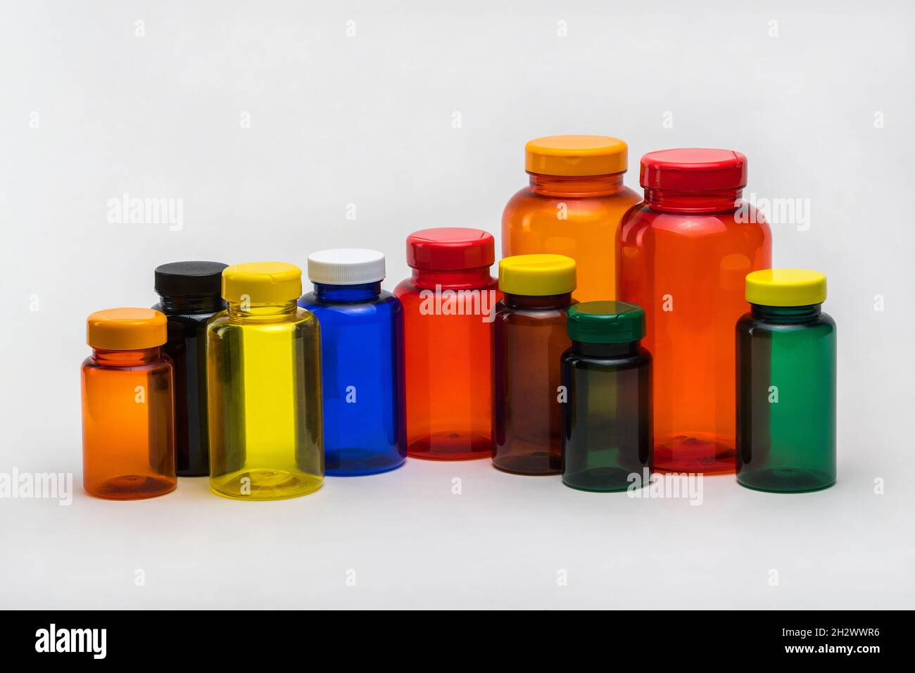 Multi colored transparent plastic pill jars on a white background ...