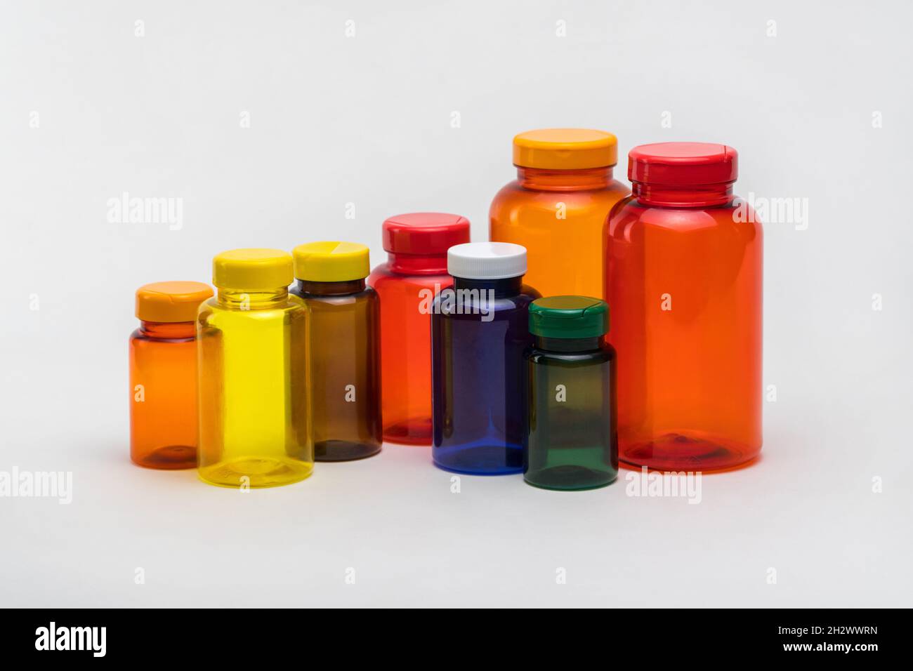 Multi colored transparent plastic pill jars on a white background ...
