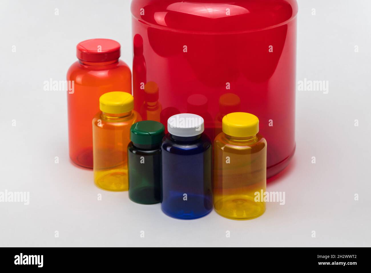 Multi colored transparent plastic pill jars on a white background ...