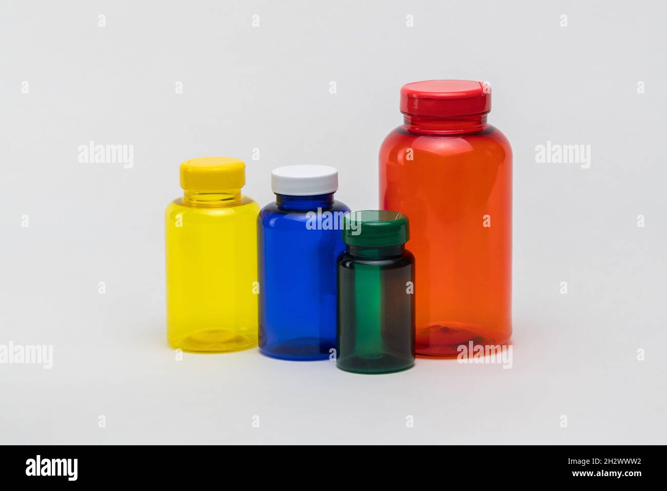 Multi colored transparent plastic pill jars on a white background ...