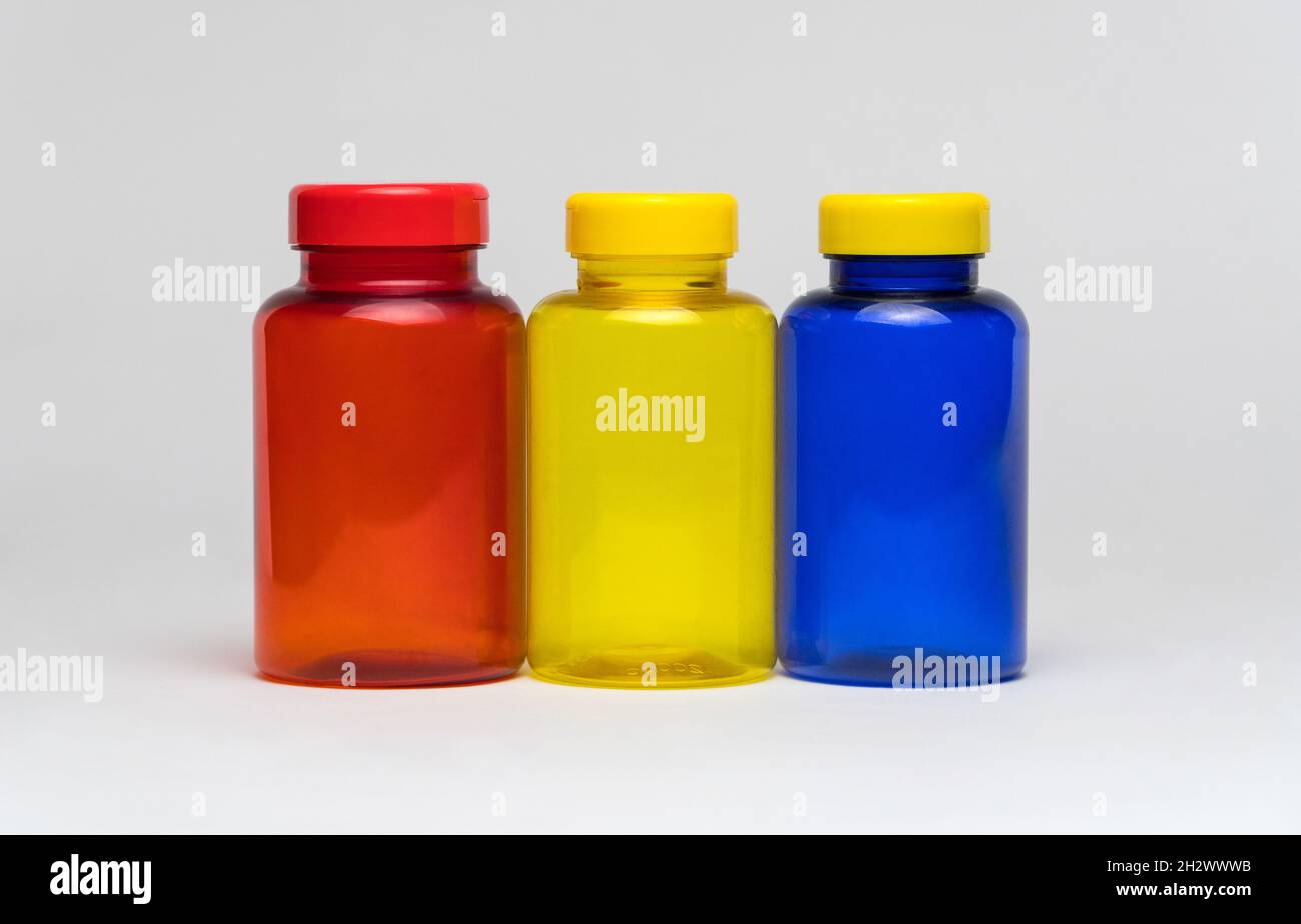 Multi colored transparent plastic pill jars on a white background ...