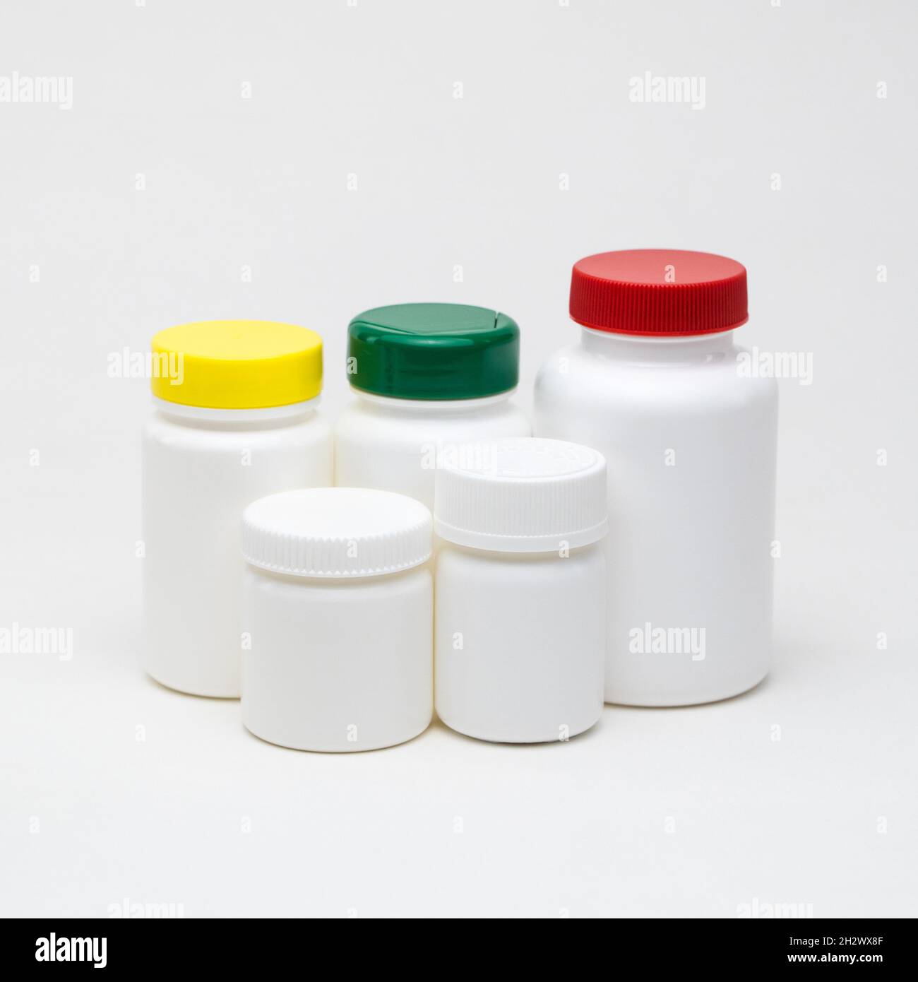 White plastic pill jars on a white background. Multi colored lids ...