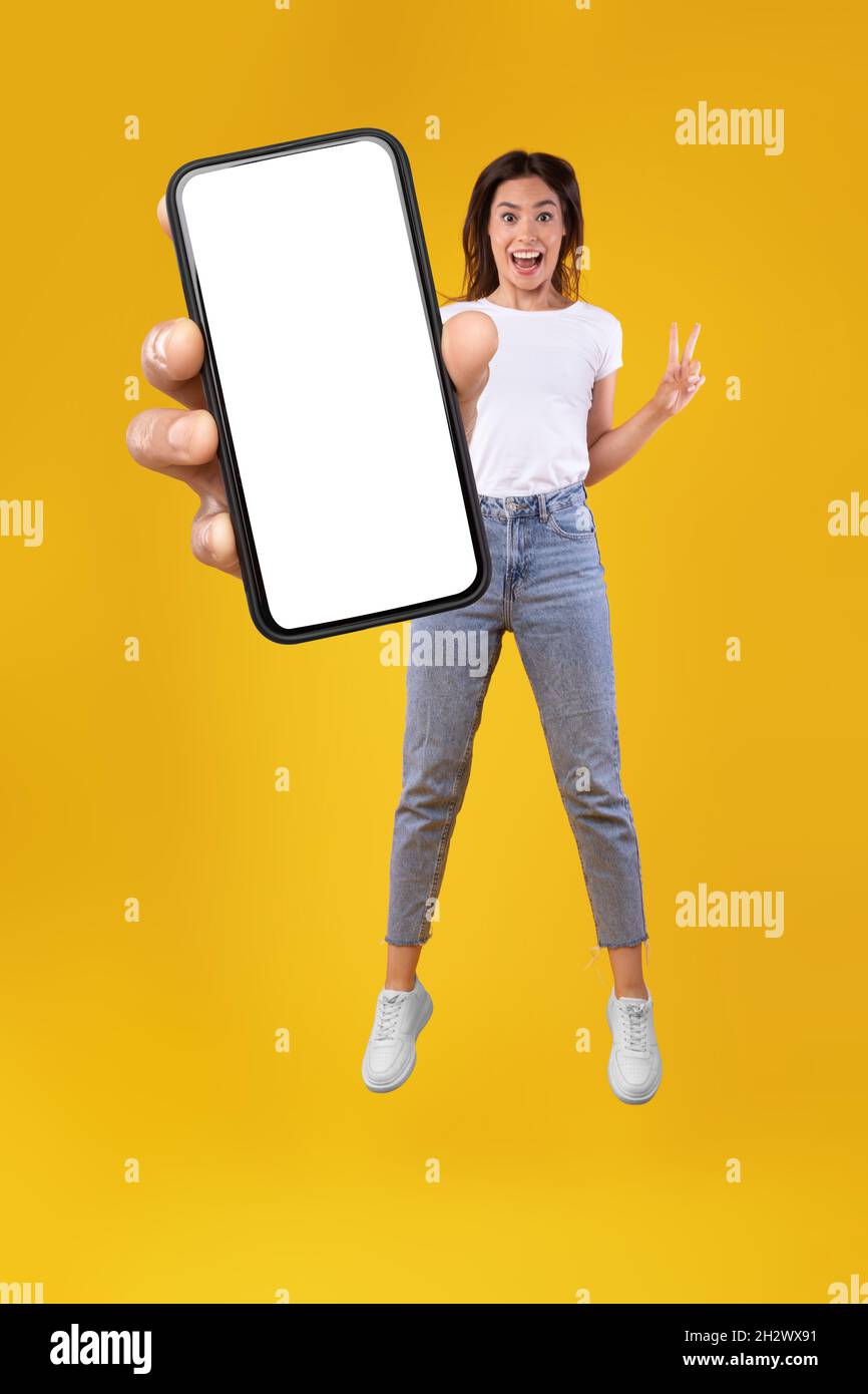 Woman showing white empty smartphone screen and jumping up Stock Photo ...