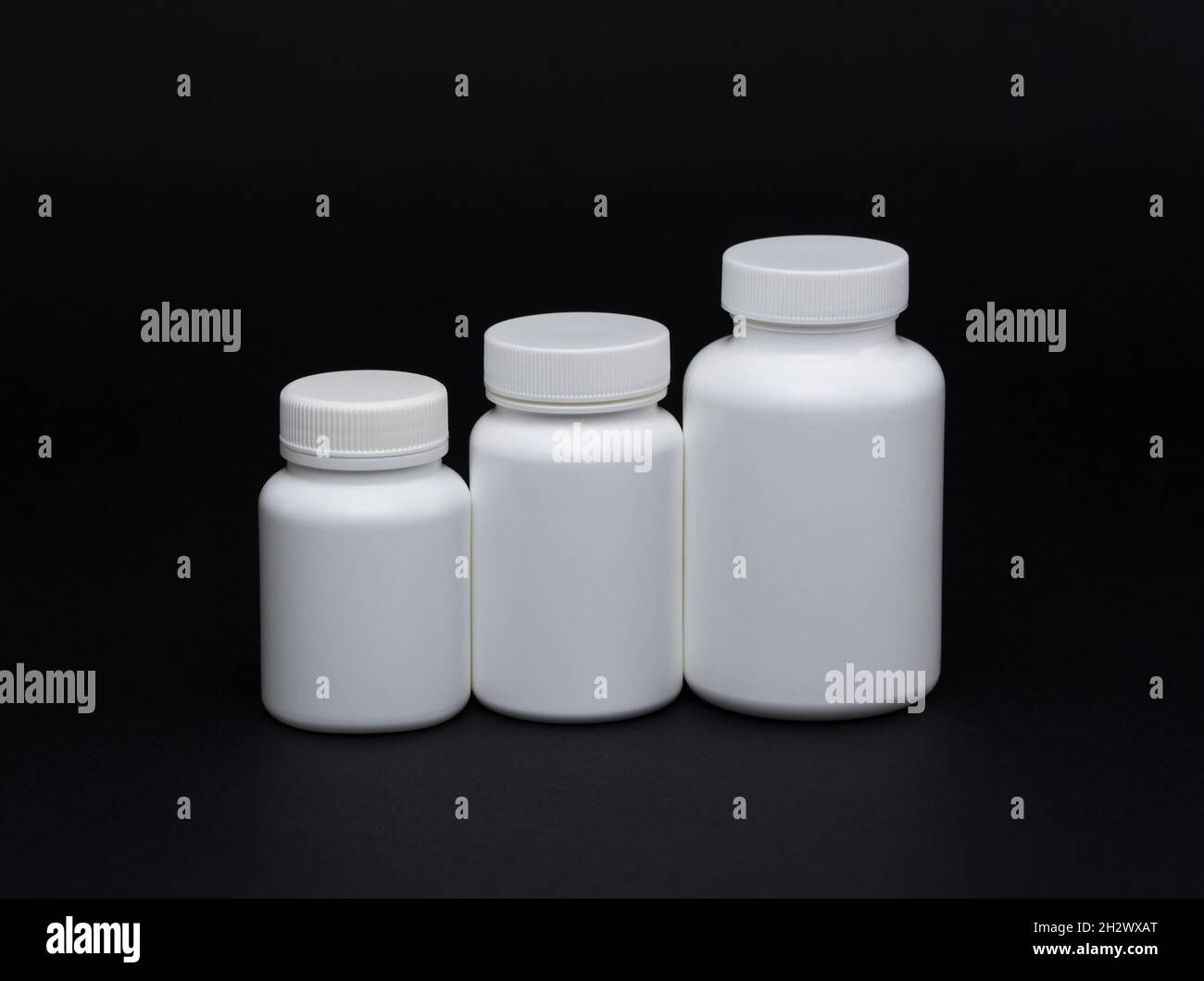 White plastic pill jars on a black background. Isolated Stock Photo - Alamy