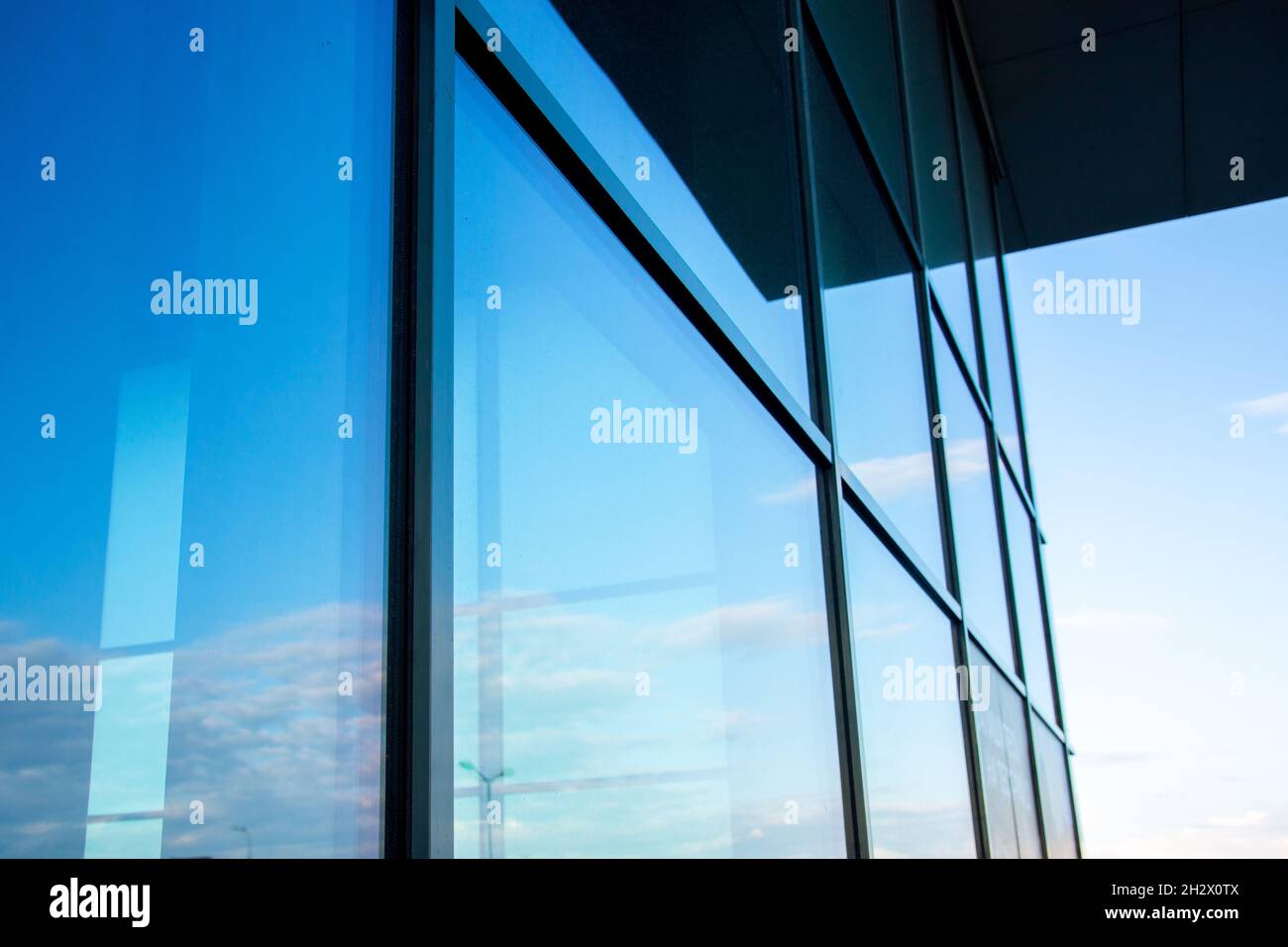 The building with glass windows reflects a blue sky. High quality photo ...