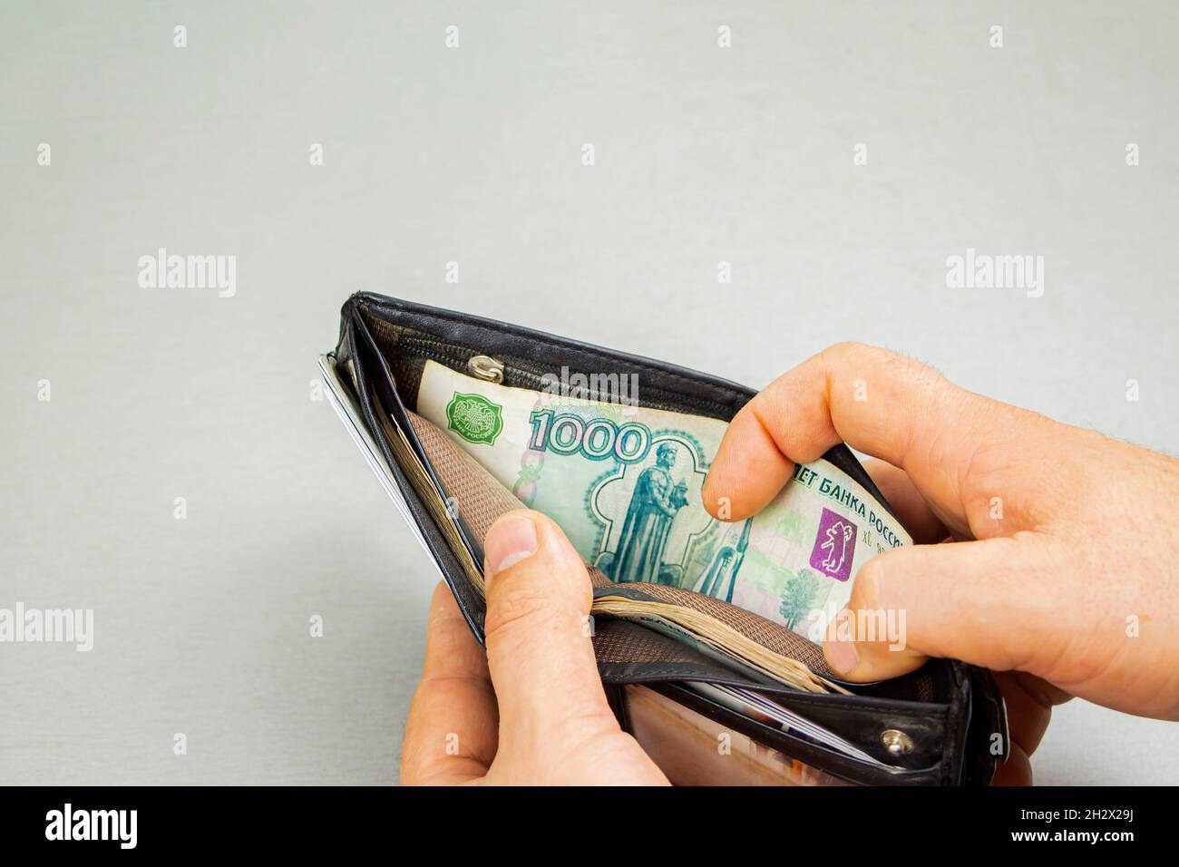 an old wallet in men's hands with Russian money, close-up, gray ...