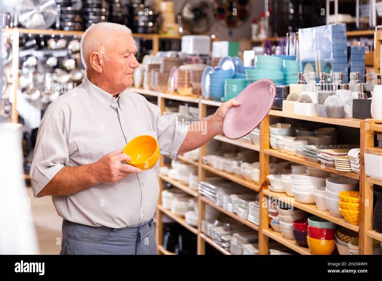 Attentive man choosing new crockery in dinnerware store Stock Photo - Alamy
