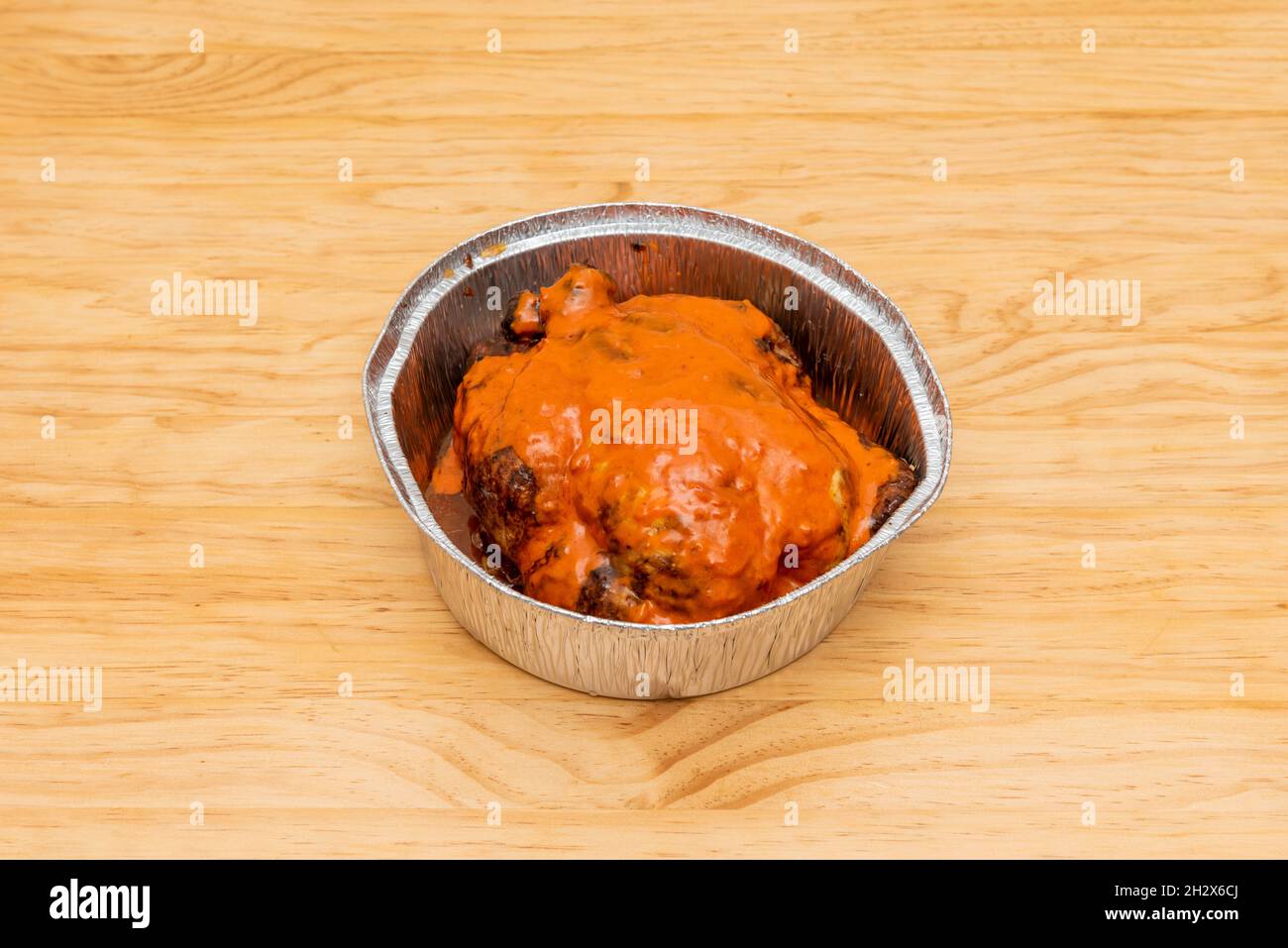 Whole charcoal-roasted chicken with mojo picon sauce on top in aluminum ...