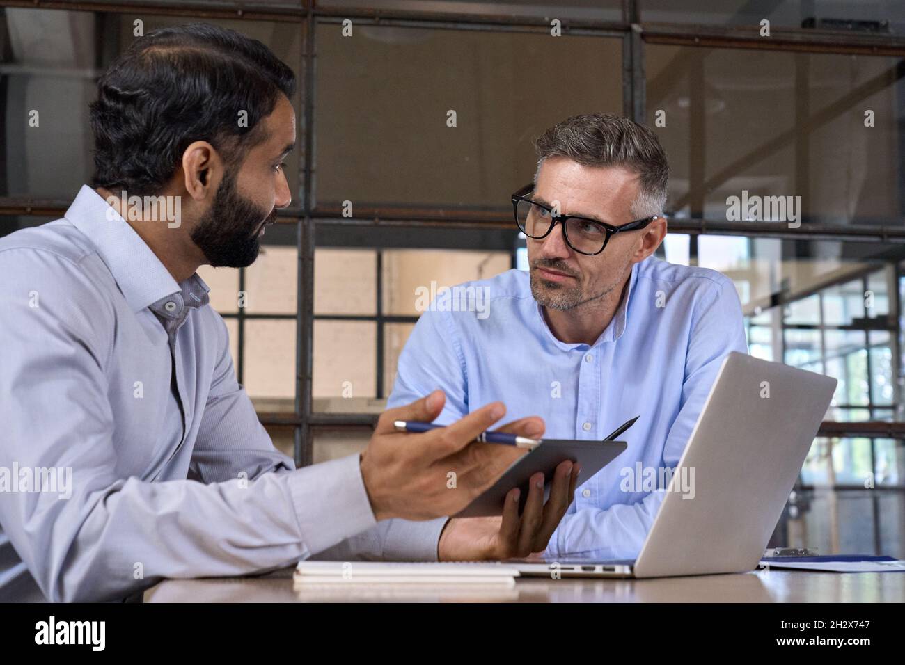 Two diverse business men discussing market data using laptop and ...
