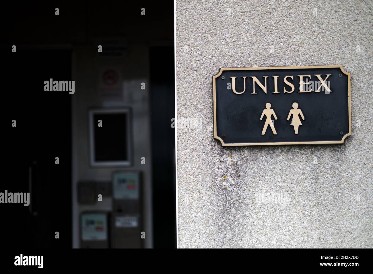 A British unisex toilet. The toilet has a clear unisex metal sign on ...