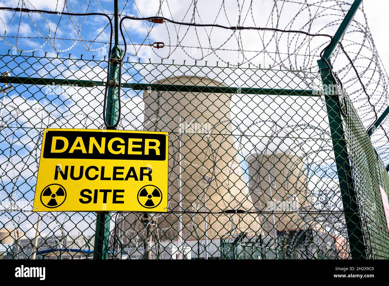 A yellow danger warning sign on the security fence of a nuclear power ...