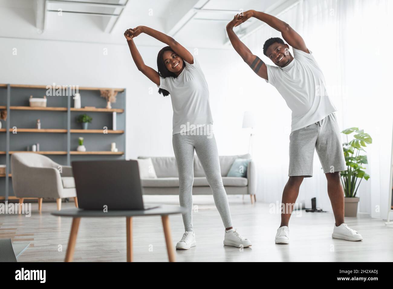 Young black couple doing side bend exercise using pc Stock Photo - Alamy