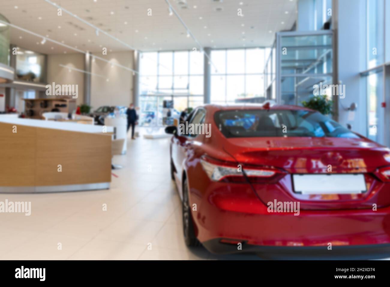 car dealer showroom interior with red car in the foreground, focus on ...