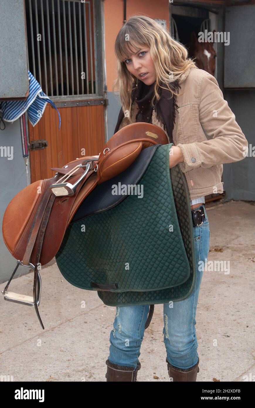 woman in the stable with the saddle before riding a horse Stock Photo ...