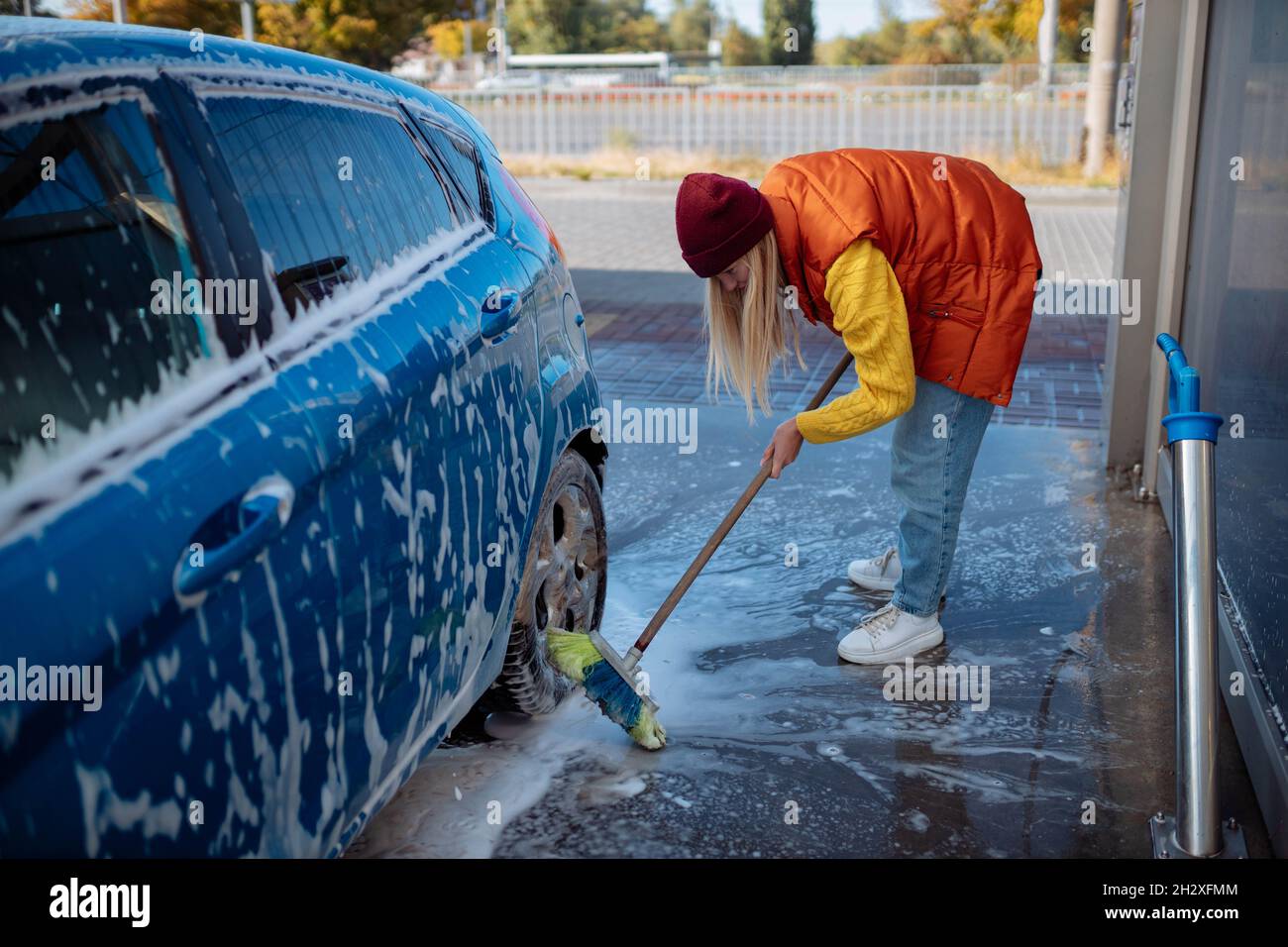 Beautiful young girl washes the car at the self-service car wash ...