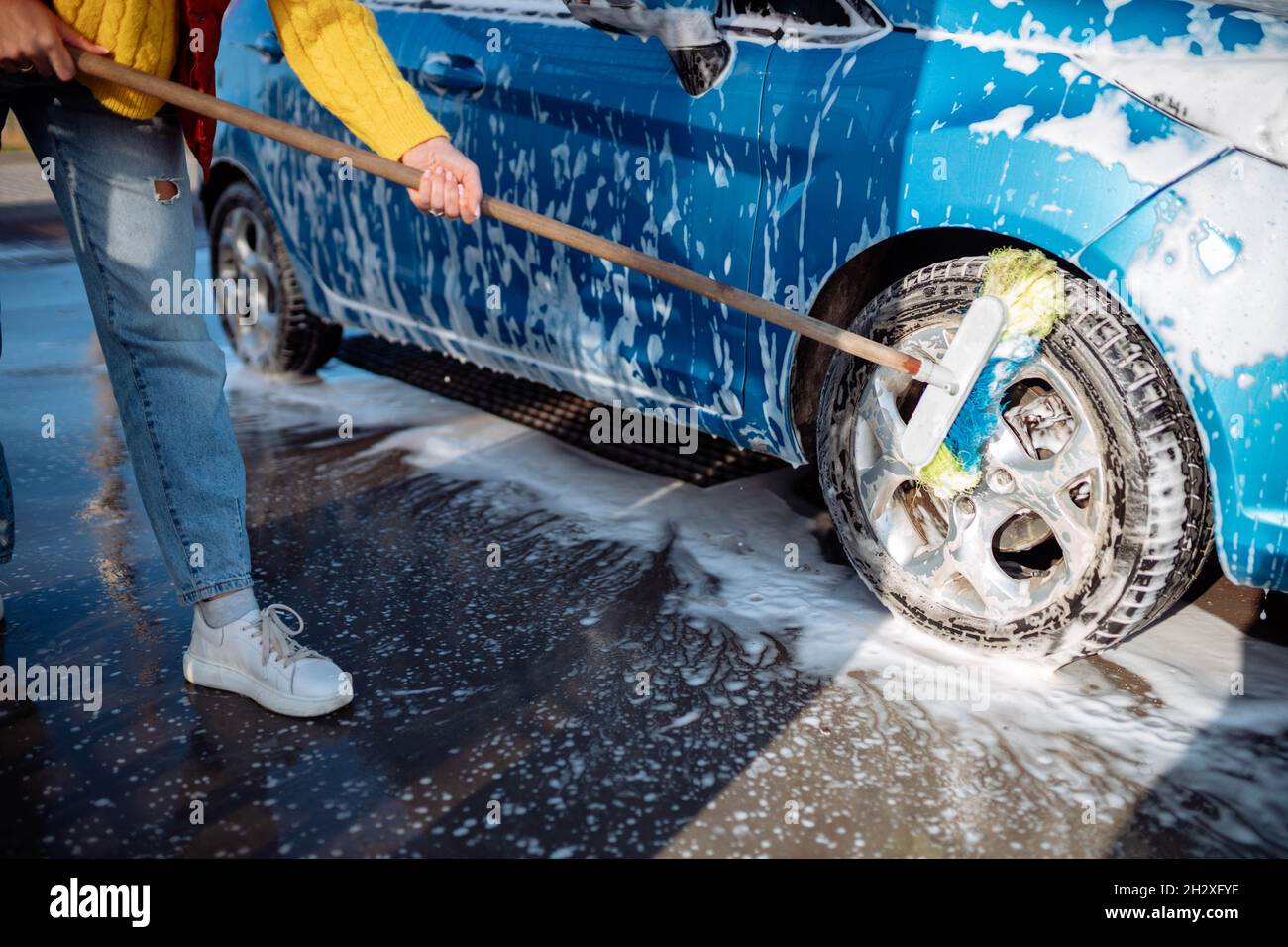 Beautiful young girl washes the car at the self-service car wash ...