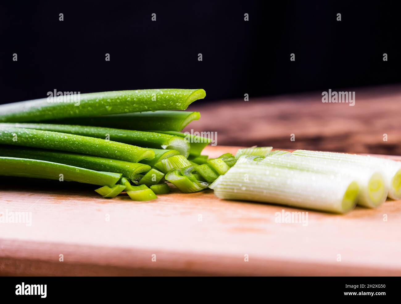 Chopped scallion or shallot or spring onion greens close up on wooden ...