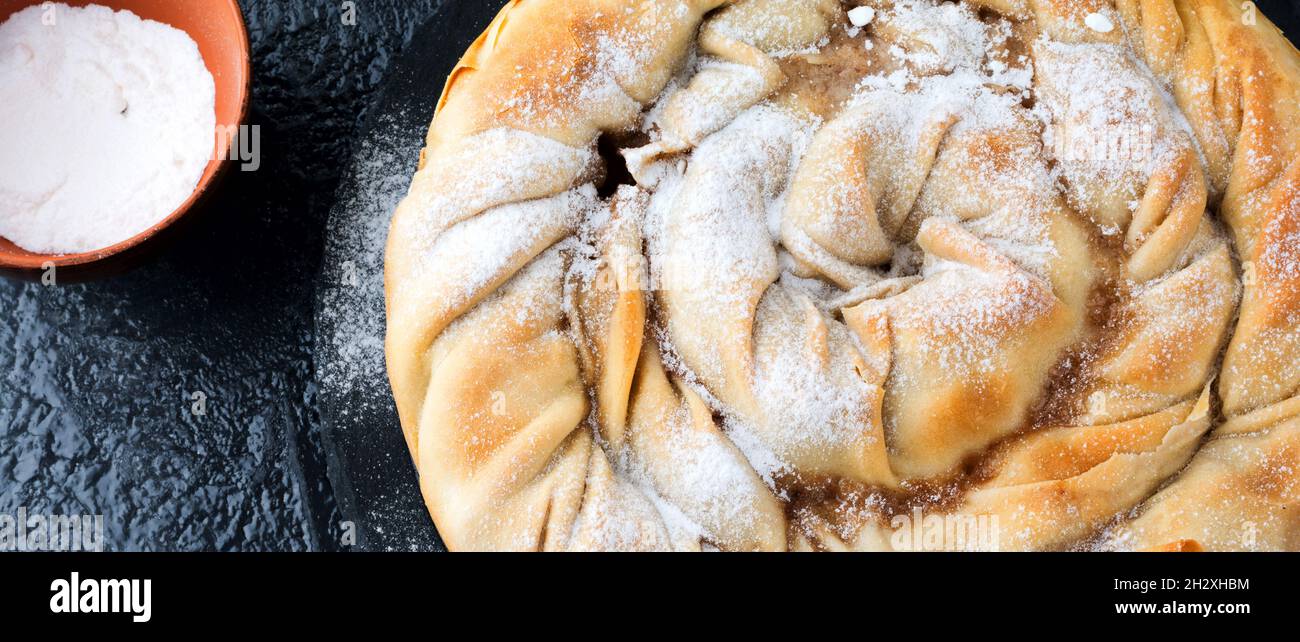 Round burek pie with an apple on a dark background. Traditional Serbian ...