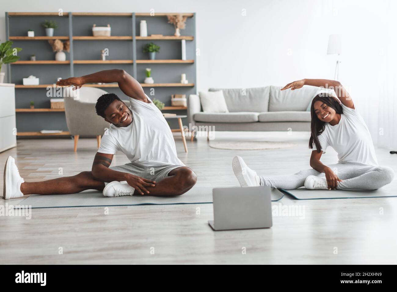 Young black couple doing side bend exercise using pc Stock Photo - Alamy