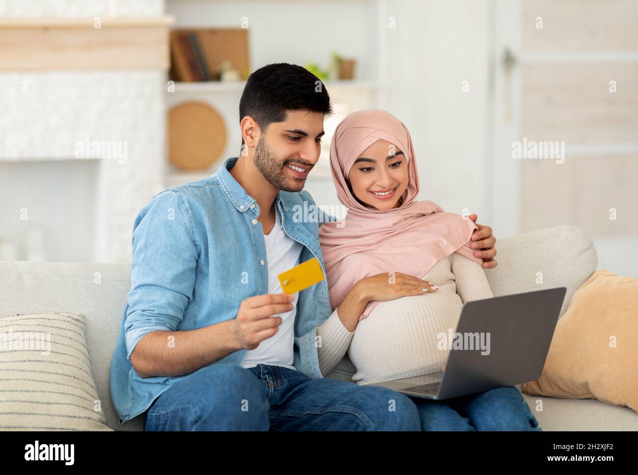 Preparing for childbirth. Loving muslim pregnant couple using laptop ...