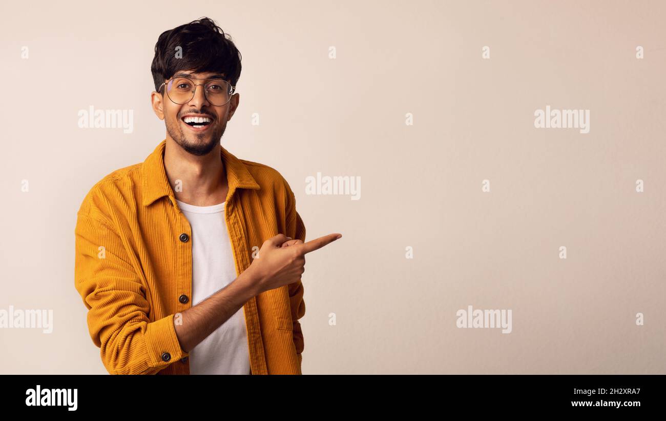 Positive young indian man pointing at copy space Stock Photo - Alamy