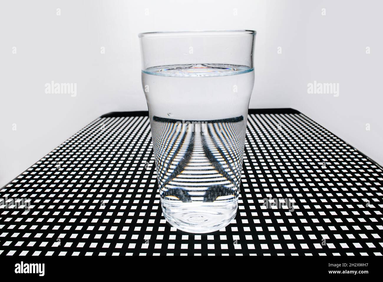 A glass on a square holed black lattice creating peculiar distortion ...