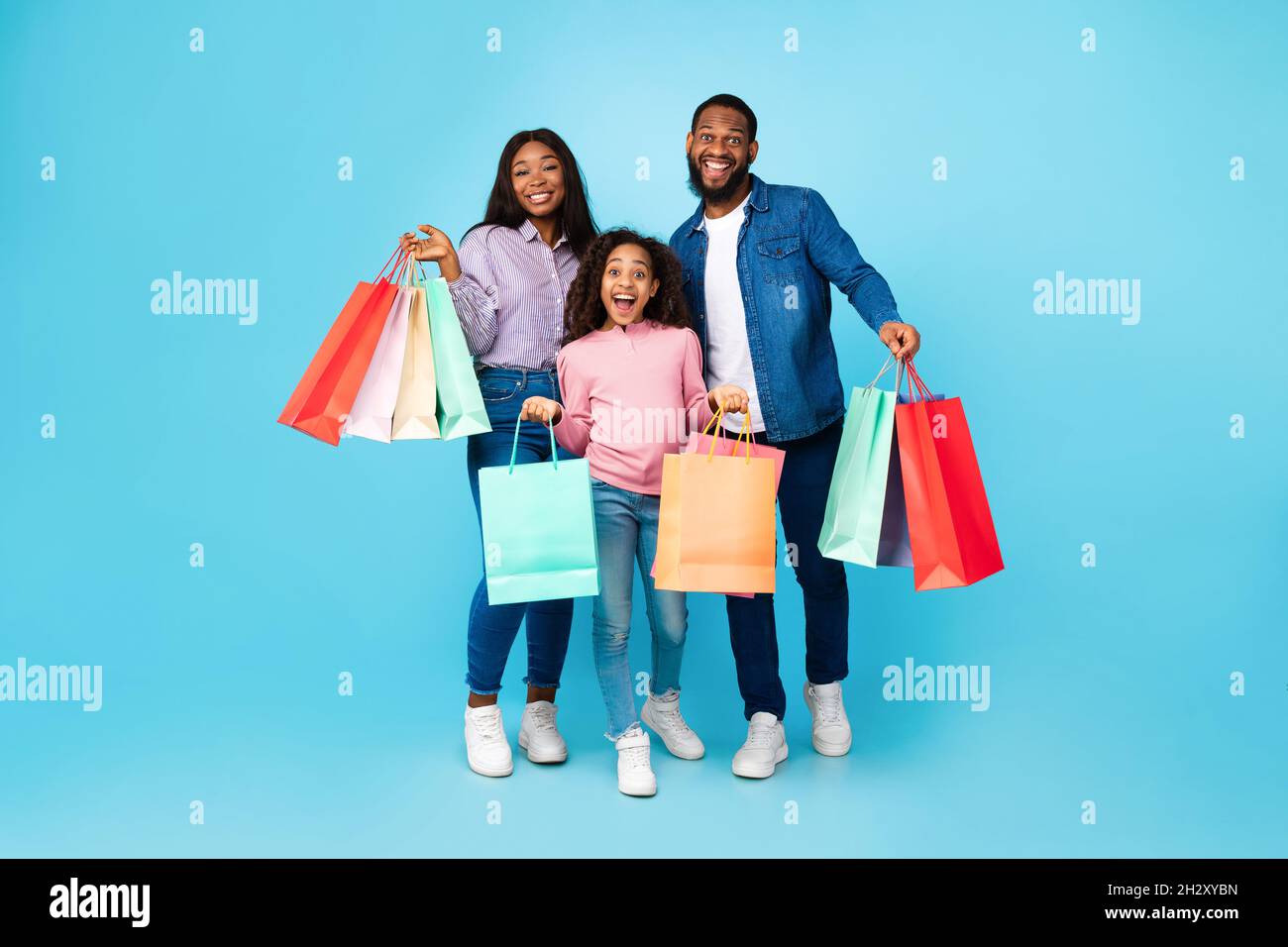 African American family of three posing with shopping bags Stock Photo ...