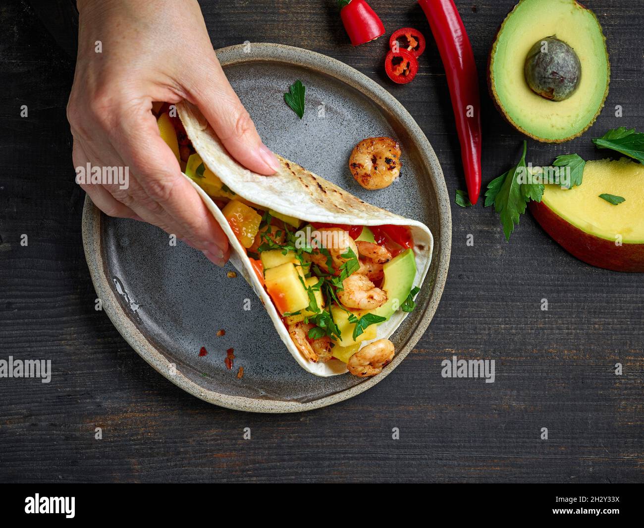 Mexican food tacos in human hand on dark wooden table, top view Stock ...