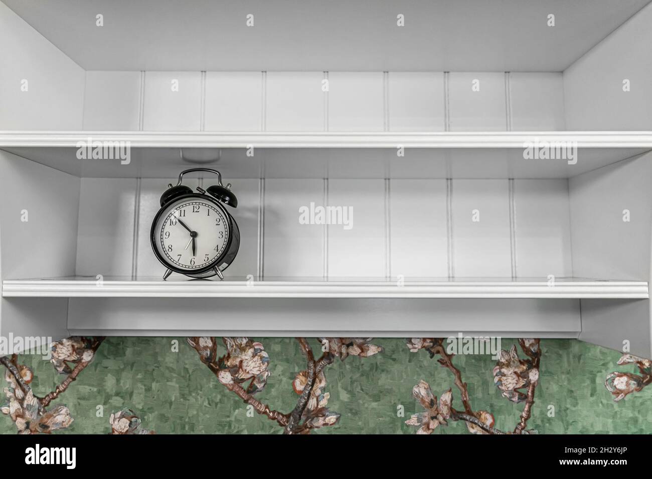 Classic vintage alarm clock on the shelf in the interior of the room ...