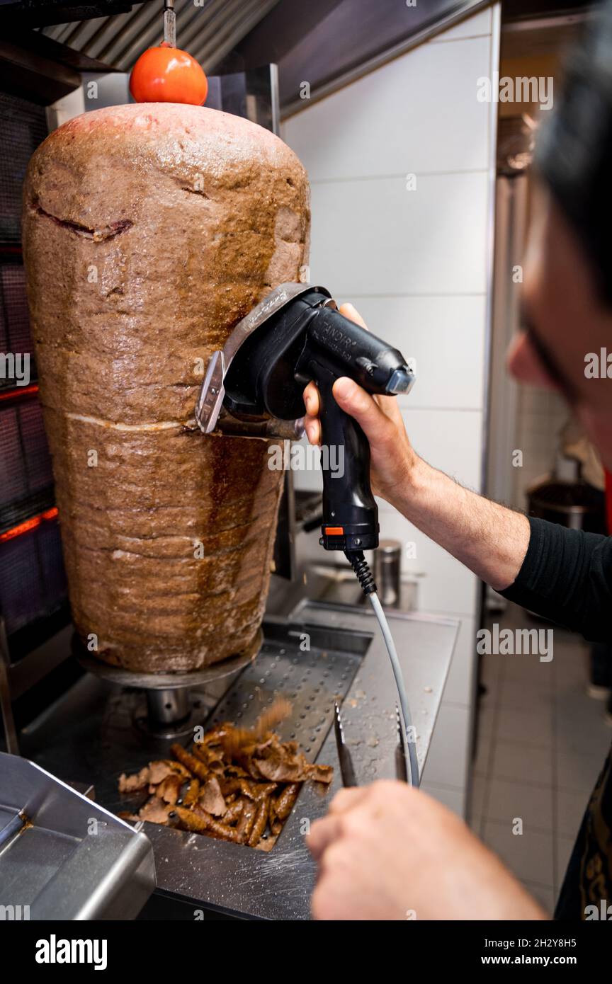 A chef carving meat from shawarma griller using akebab slicer Stock ...
