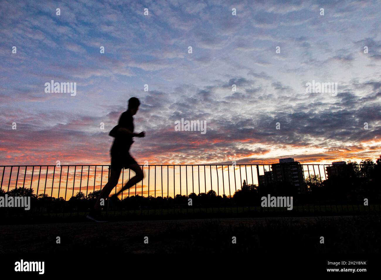 Running as the sun sets in an urban park in London with a tower block ...