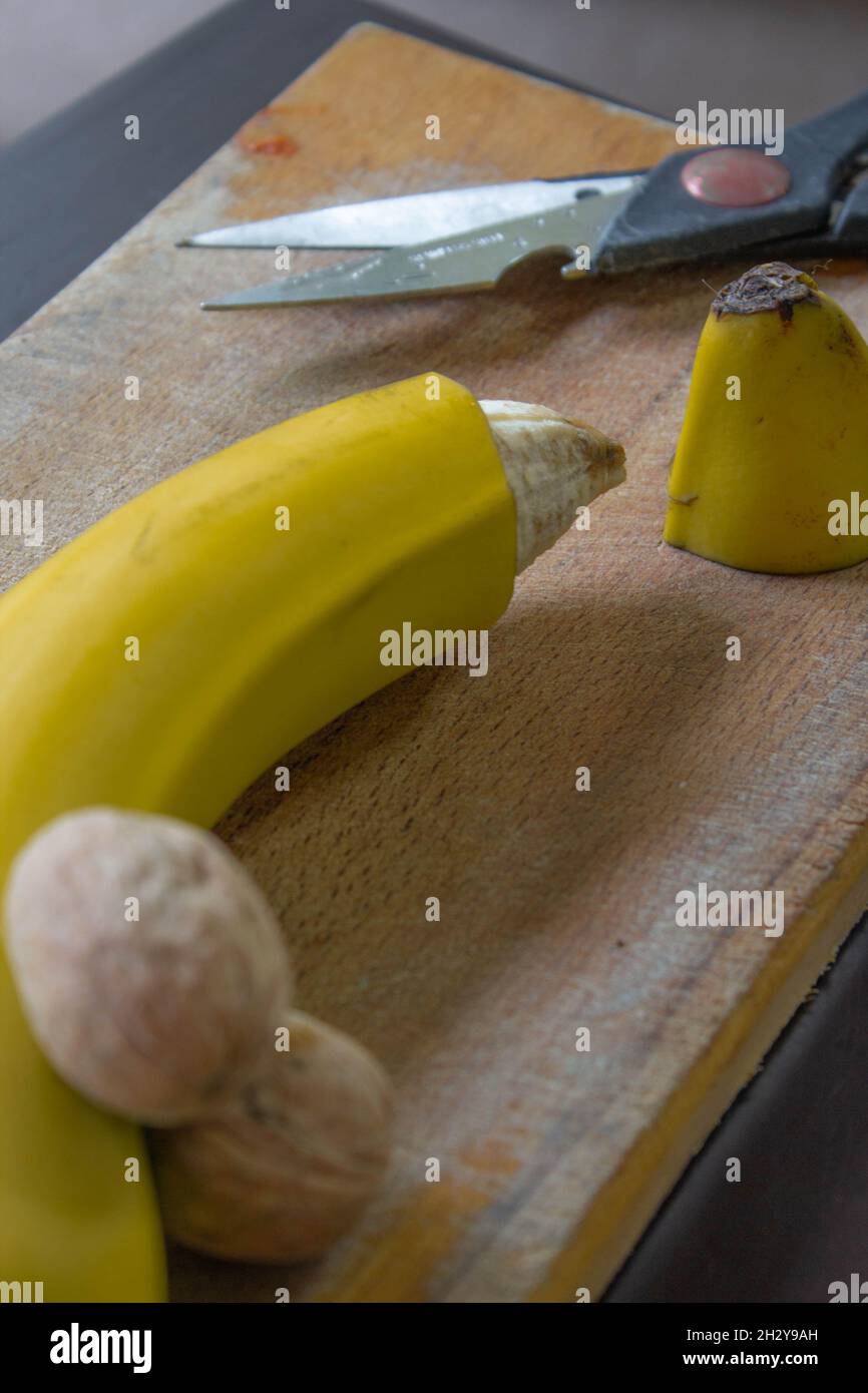 A circumcised penis figure symbolized by banana and walnuts on a wooden ...