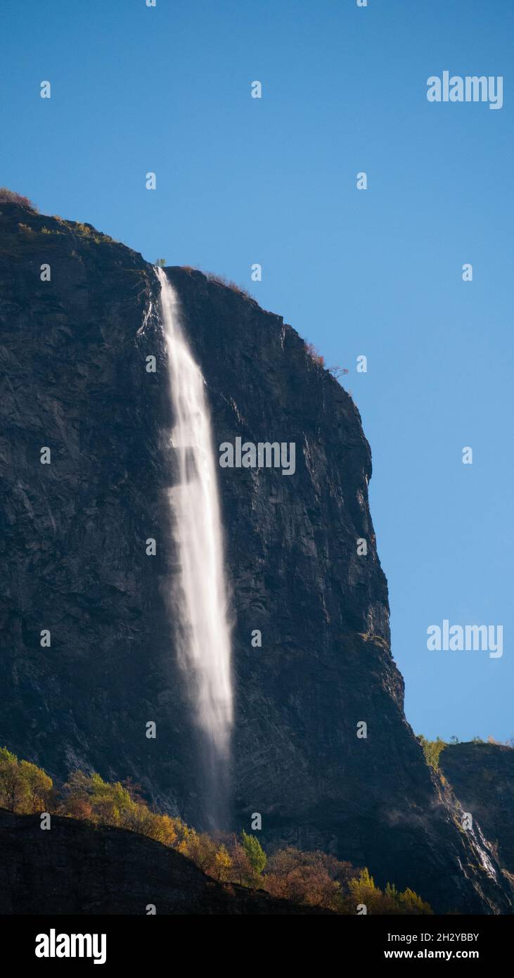 A low angle panoramic view of a high cliff with a waterfall under a ...