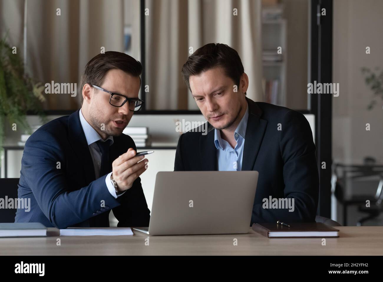 Young man insurance broker consult client on workplace before pc Stock ...