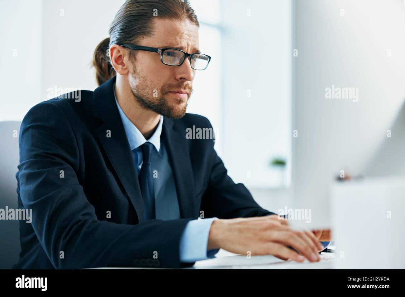 business man in a suit with glasses in the office at his desk Stock ...