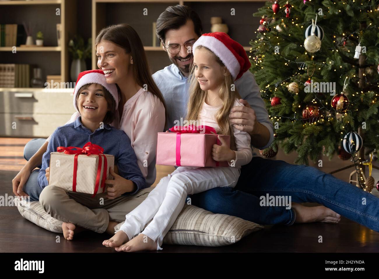 Happy bonding family sitting on floor with wrapped gifts Stock Photo ...