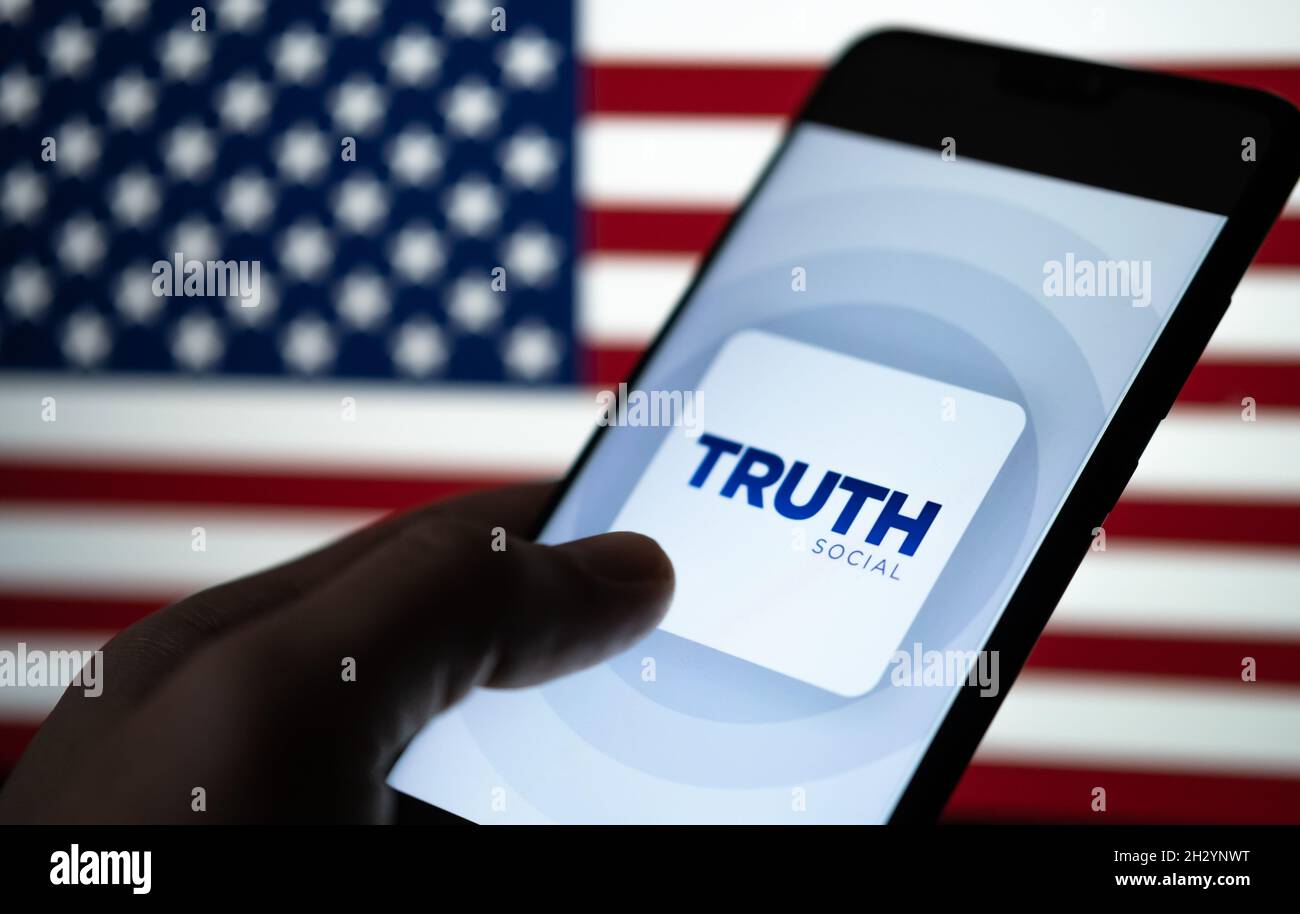 Truth Social app logo seen on the smartphone and blurred flag of ...