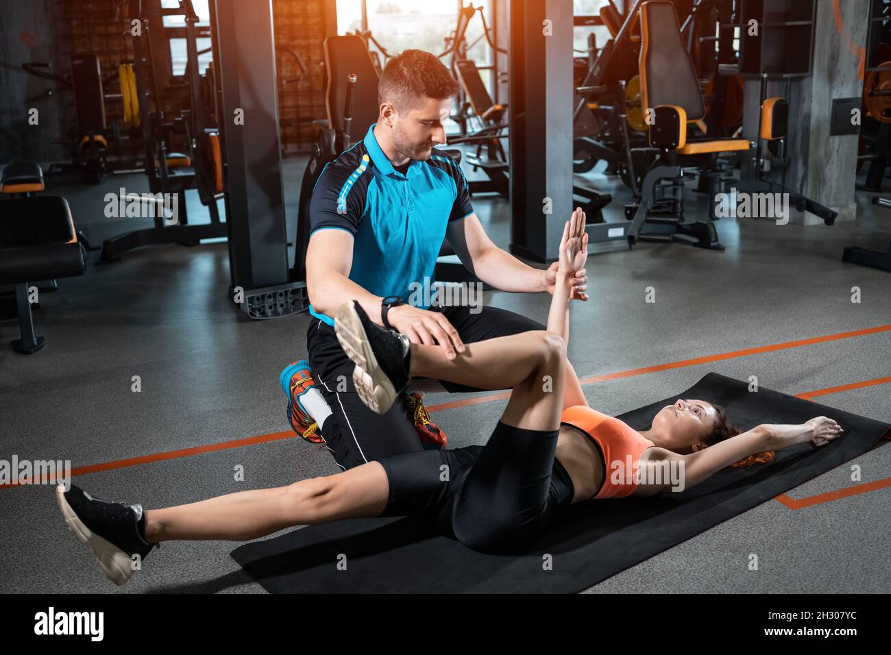 young woman exercising dead bug with personal trainer in gym Stock ...