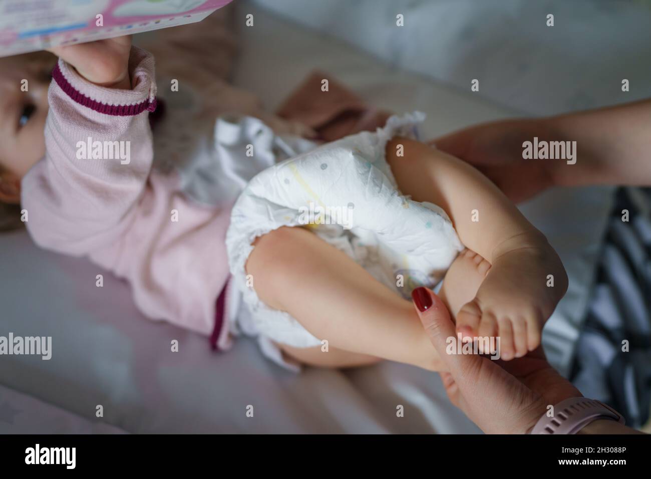 Close up hands of unknown caucasian woman mother changing diapers to her six months old baby ...
