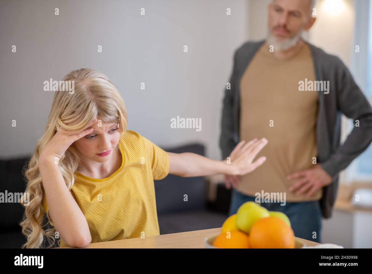 A blonde cute girl feeling frustrated while her father shouting at her ...