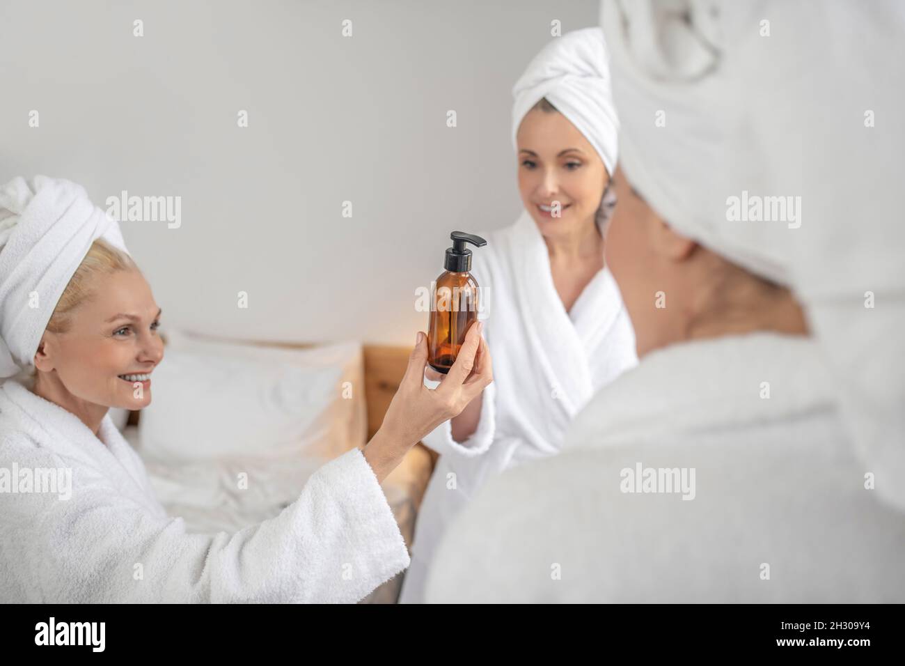 Three women with delight looking at cosmetic product Stock Photo - Alamy