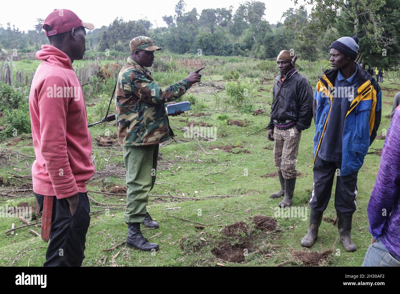 A Kenya forest service ranger speaks to a group of men who were ...