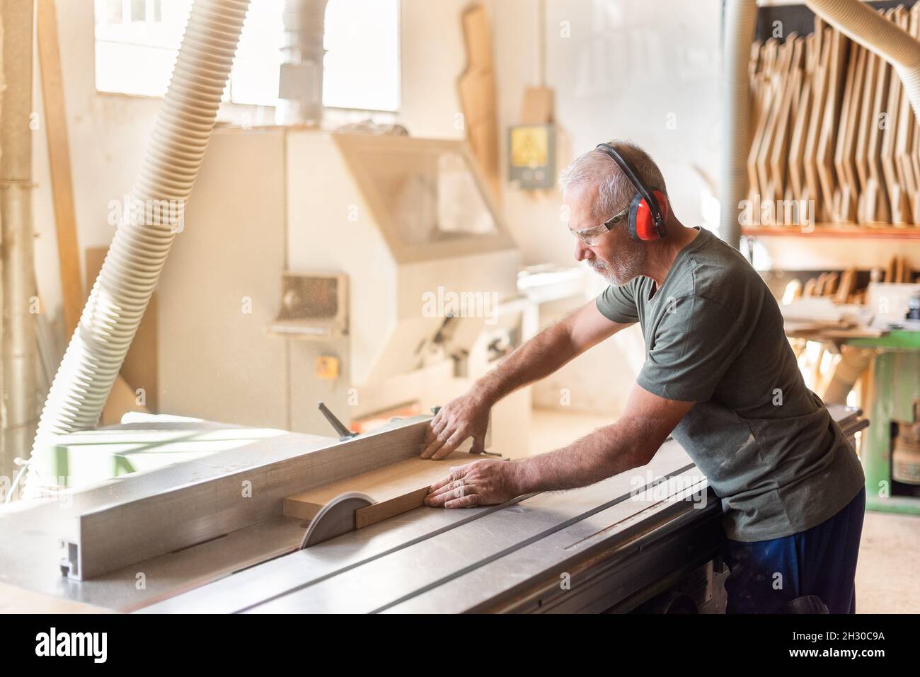 Man at work cutting timber on a sliding table saw Stock Photo - Alamy