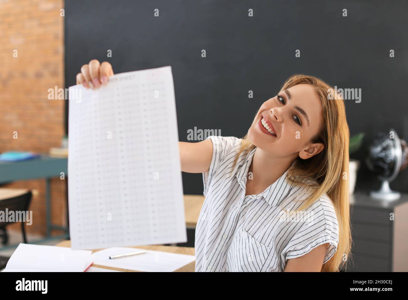 Happy student with answer sheet for school test in classroom Stock ...