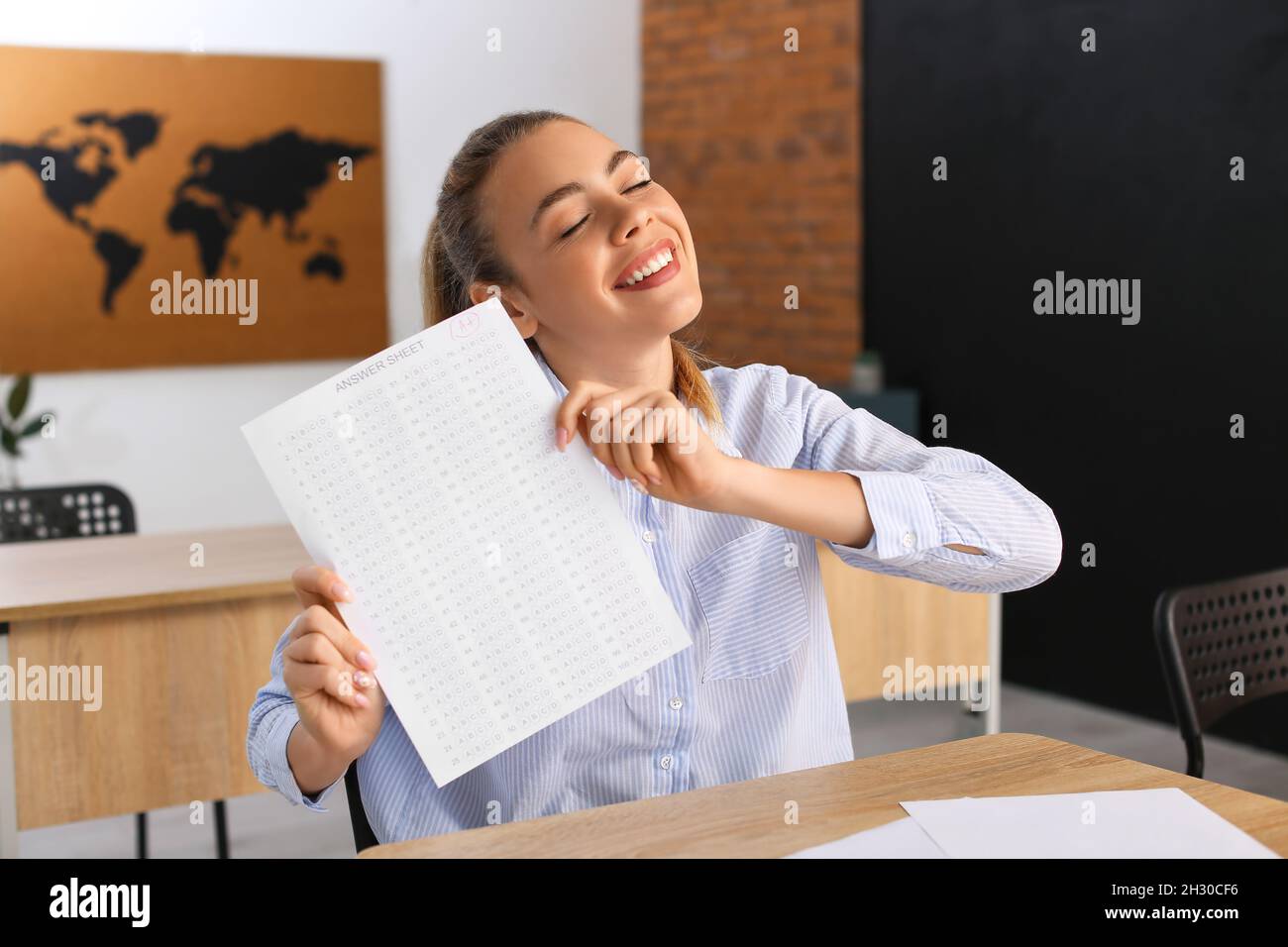Happy student with answer sheet for school test in classroom Stock ...