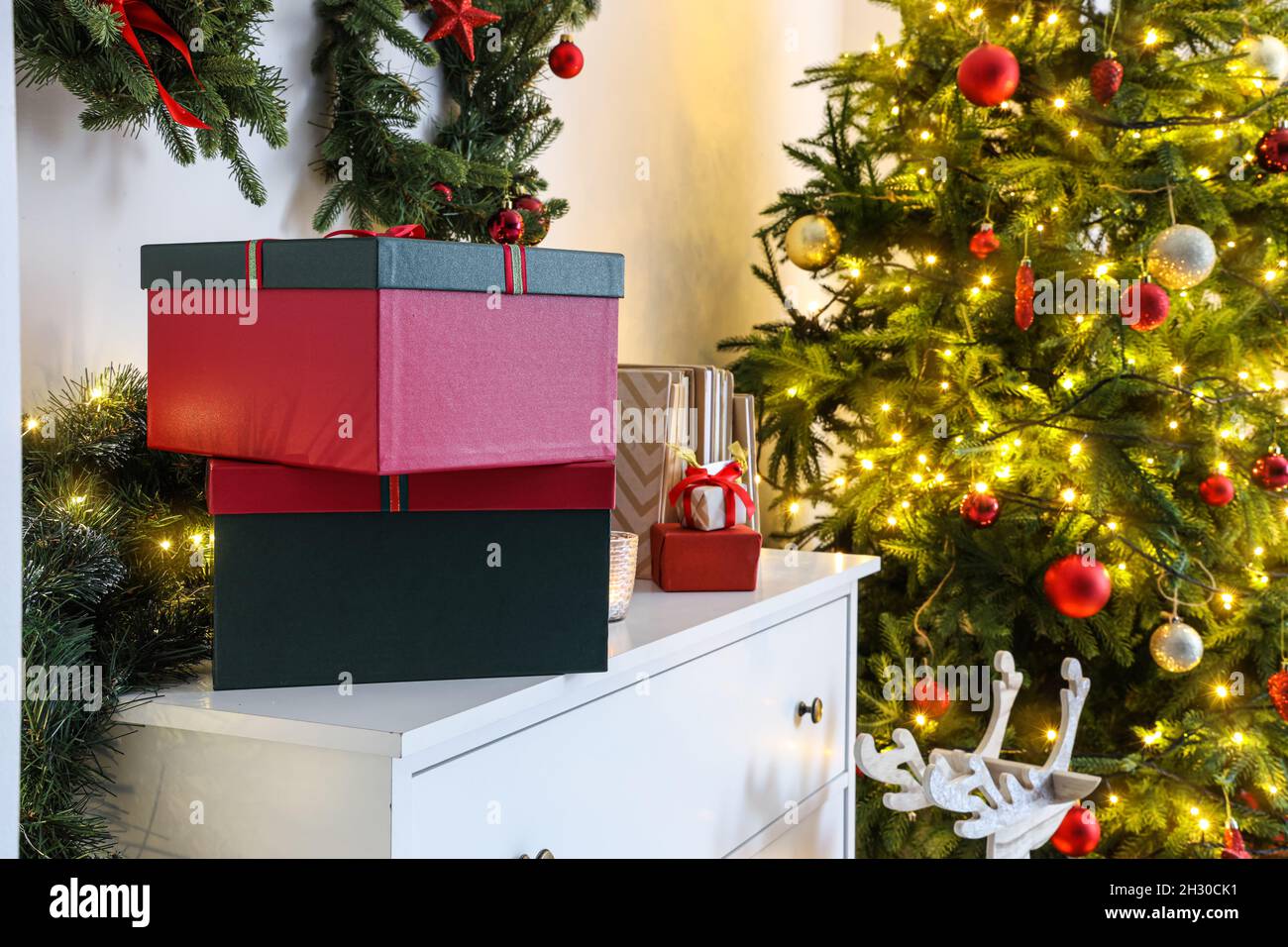Beautiful Christmas gifts on chest of drawers in room Stock Photo - Alamy