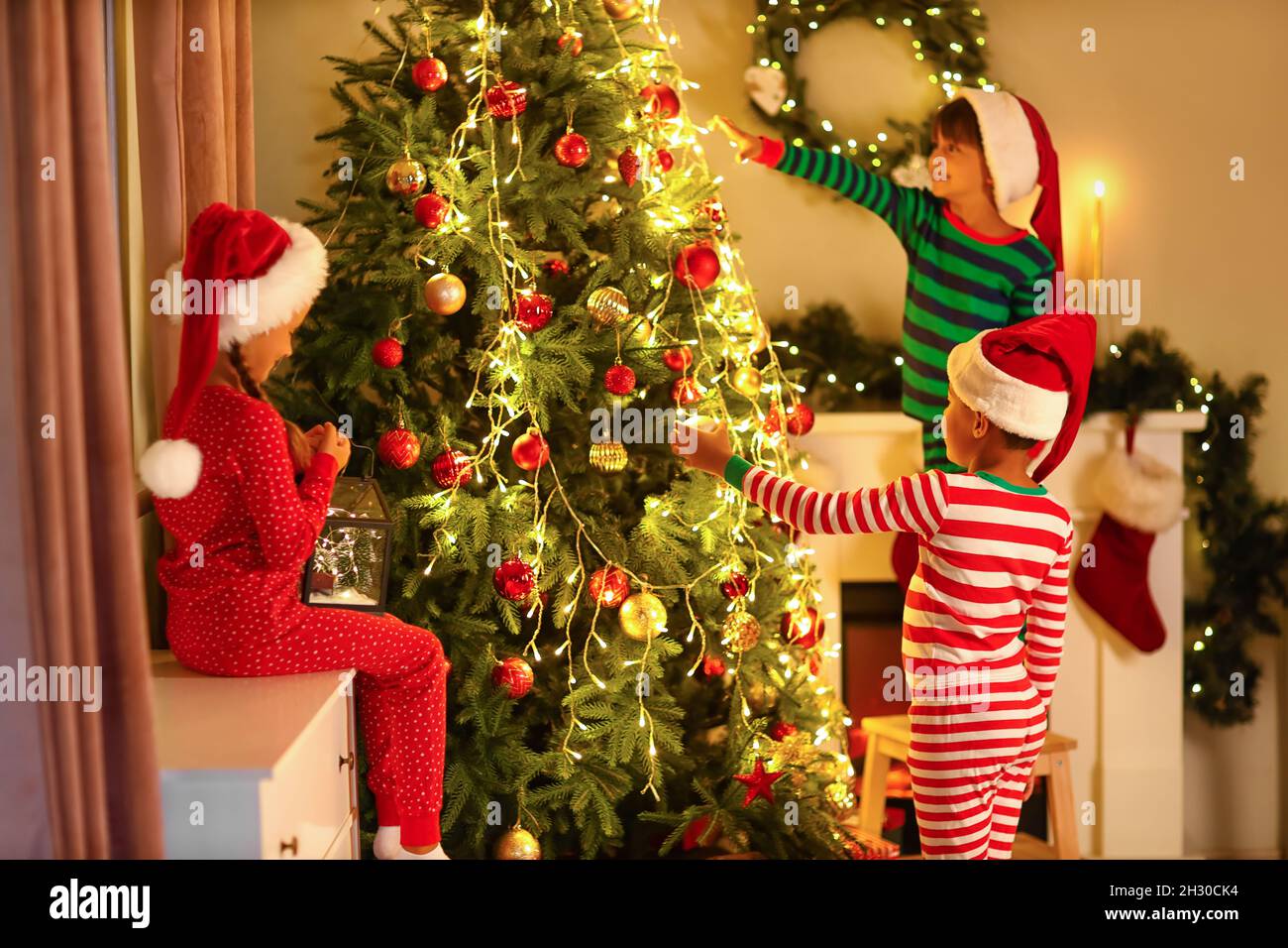 Little children decorating Christmas tree at home in evening Stock ...